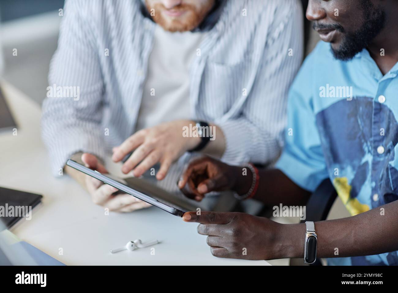 Two colleagues discussing project while using tablet device in vibrant ...