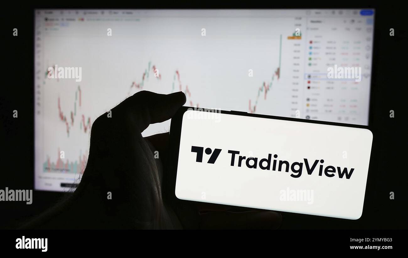 Stuttgart, Germany, 06-12-2024: Person holding mobile phone with logo of American trader social ...