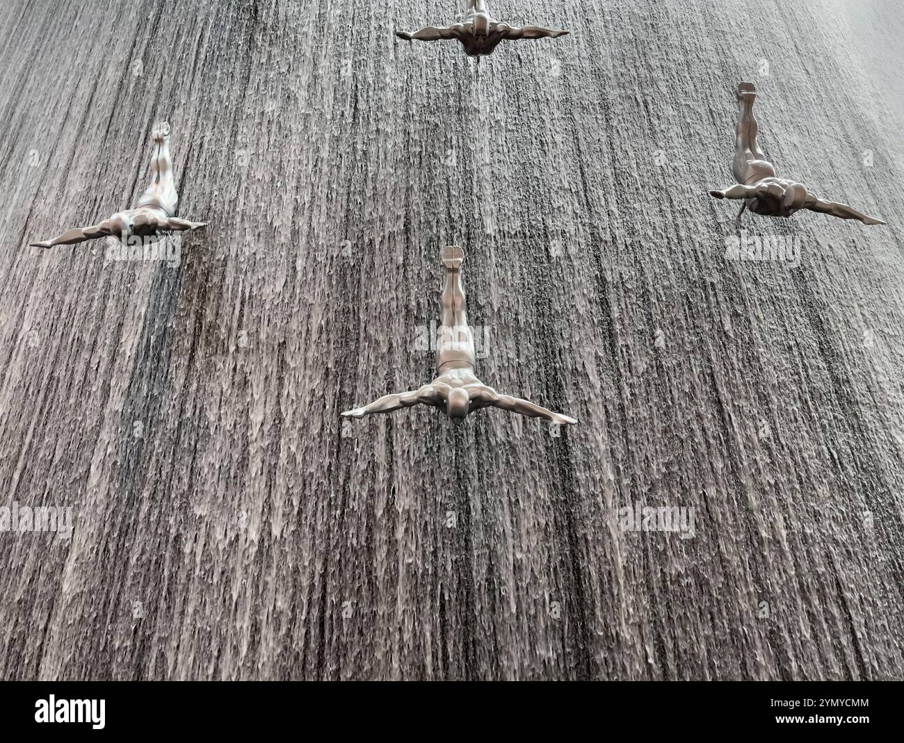 Four divers are shown diving headfirst from a tall waterfall, with ...