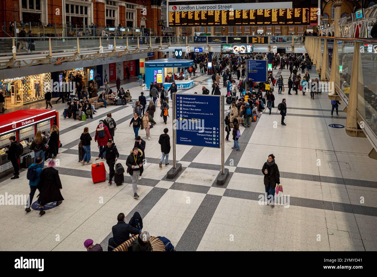Liverpool St. Passengers wait for trains and watch the station boards ...