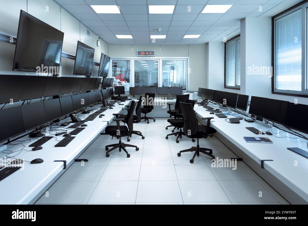 A modern office with rows of computer workstations along the walls. The ...