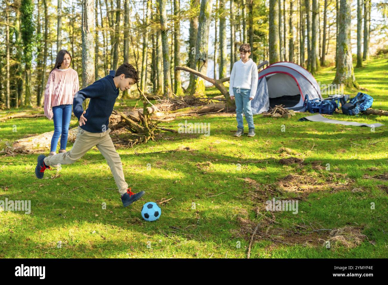 Caucasian young members of a family playing football in the forest ...