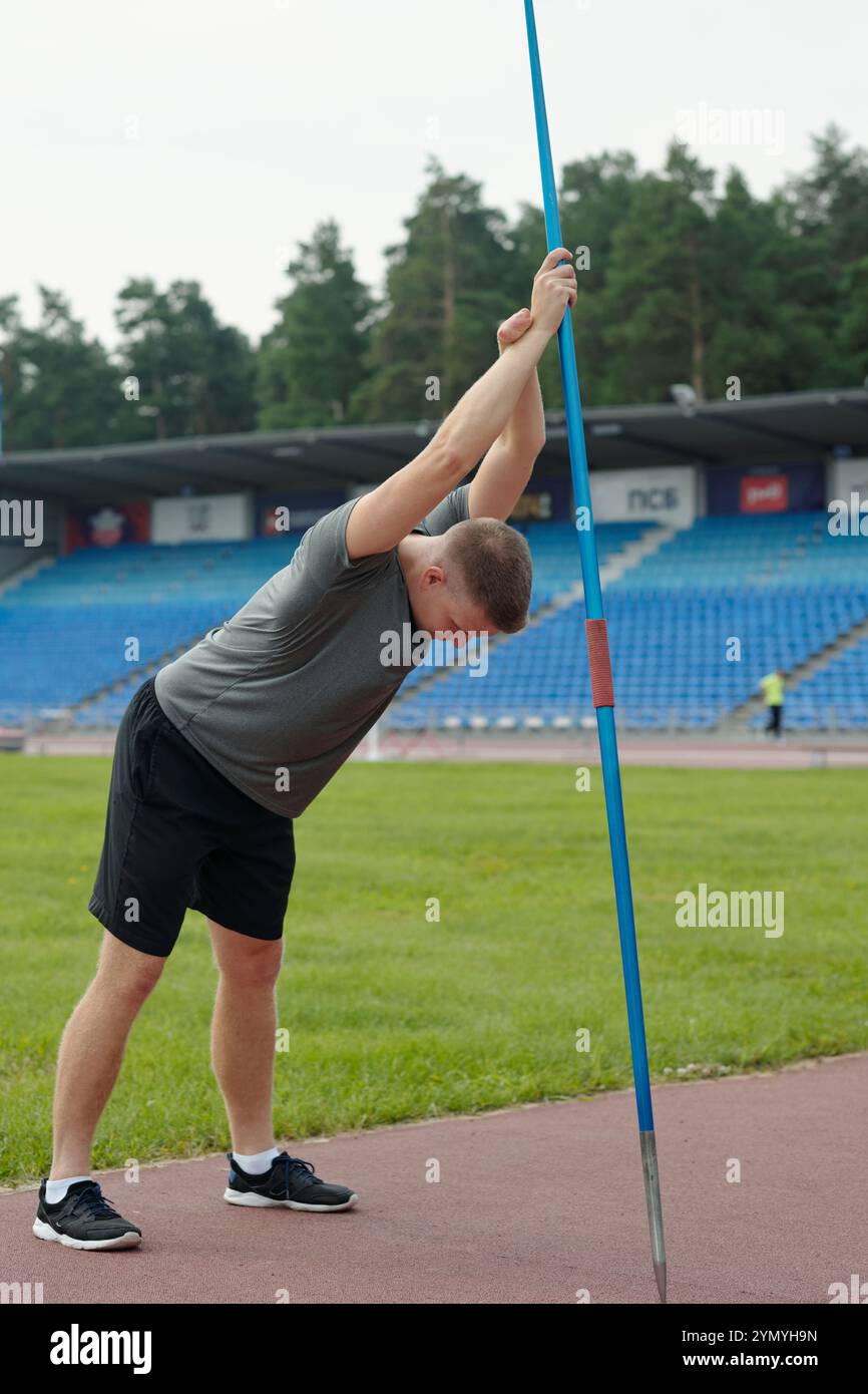 Athlete preparing for pole vaulting by stretching with pole on athletic ...