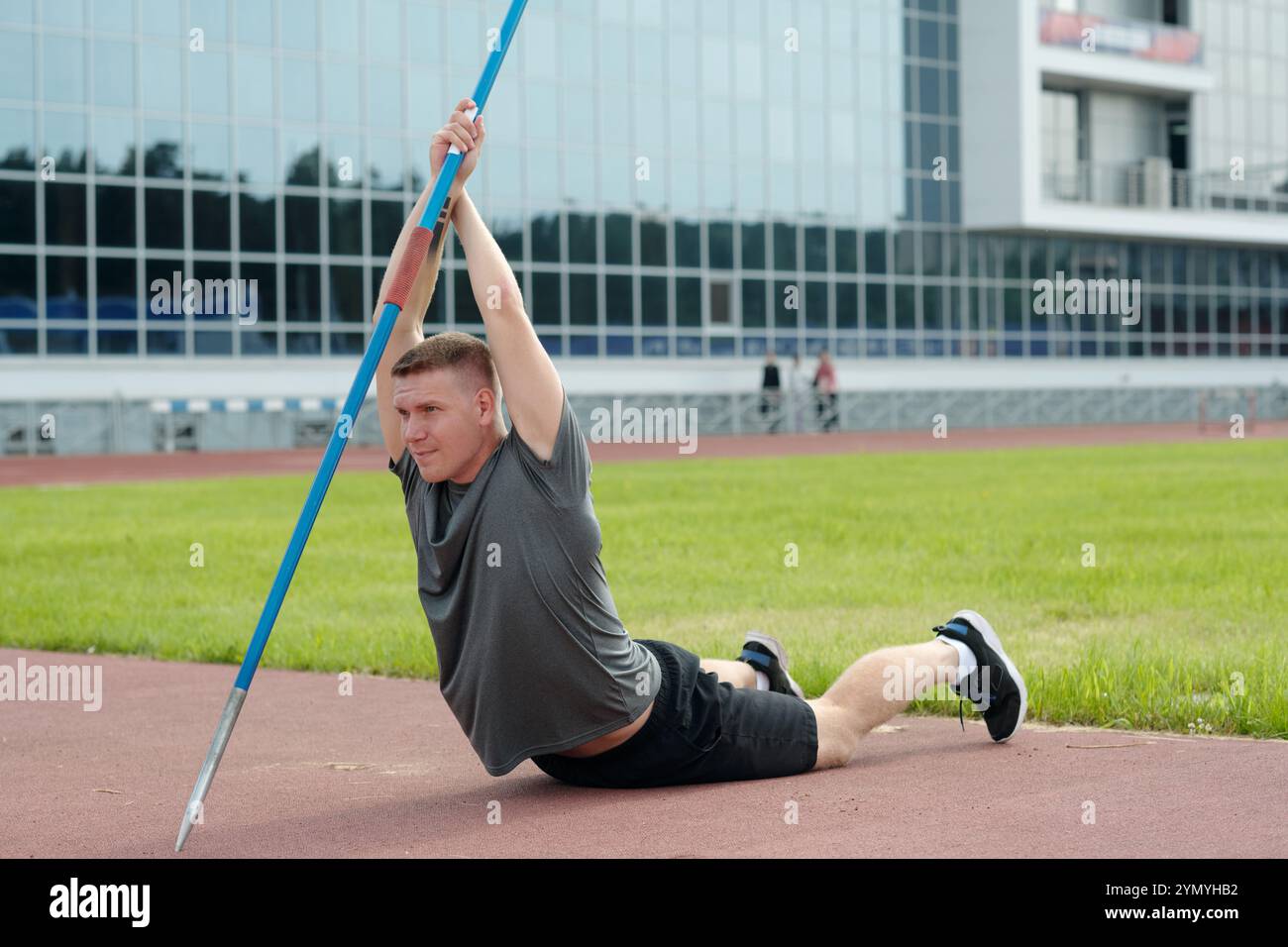 Athlete practicing pole vault on sports field near stadium, showing ...