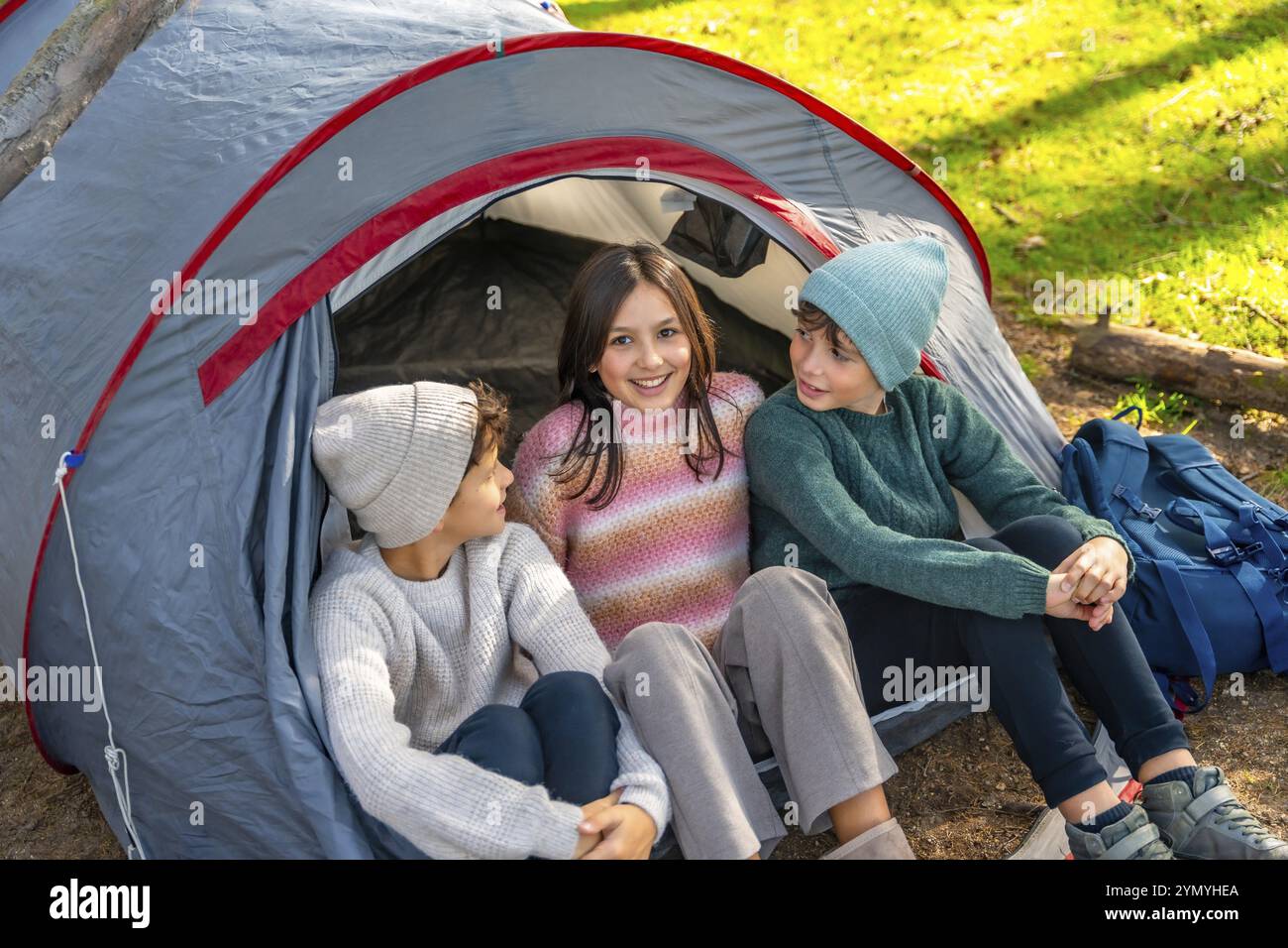 Sister and brothers enjoying sitting on camping tent in the forest ...