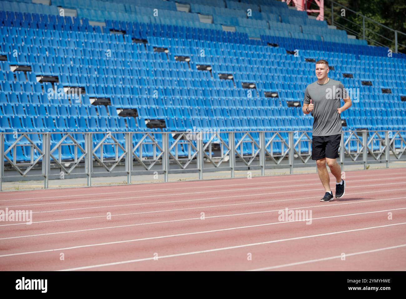Man jogging on running track in empty stadium during daytime Practicing ...