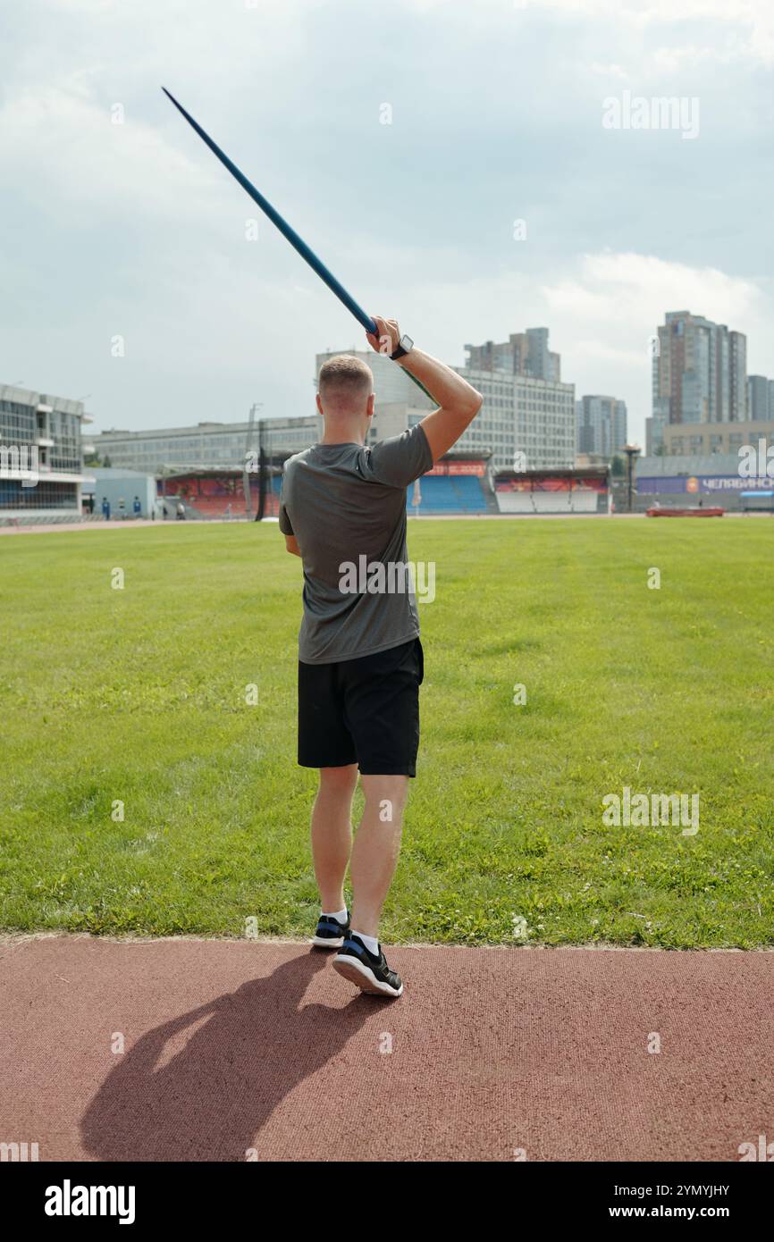 Person preparing to throw javelin on an athletic field with buildings ...