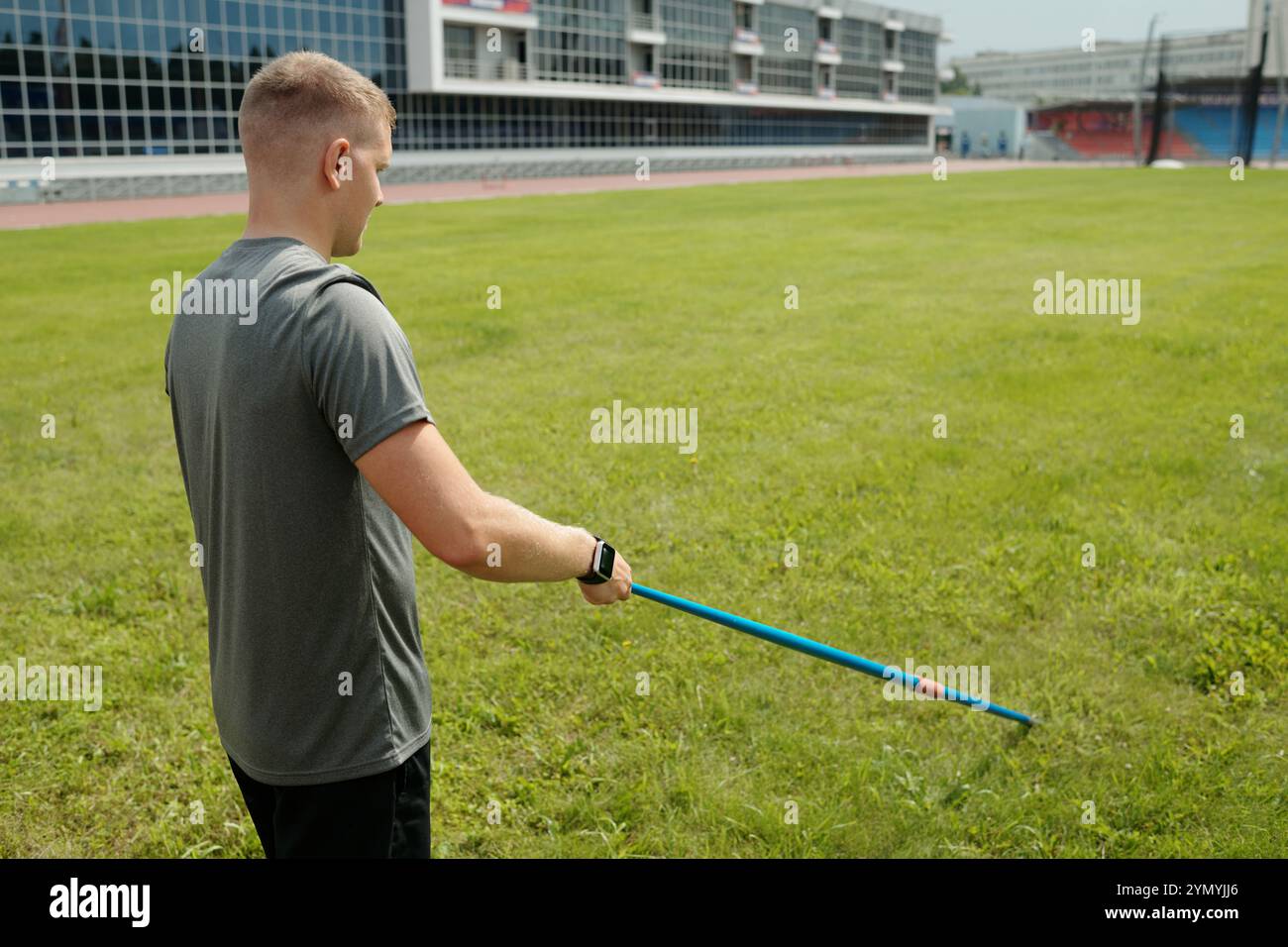 Athlete holding a pole vaulting pole on an outdoor field near sports ...