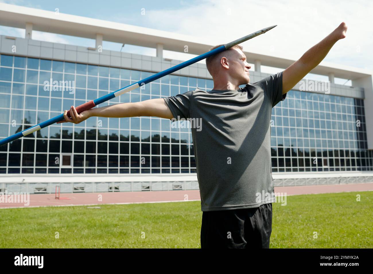 Athlete preparing to throw javelin in stadium with arm positioned for ...
