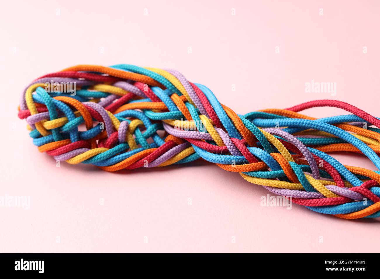 Colorful ropes tied together on pink background, closeup. Unity concept ...