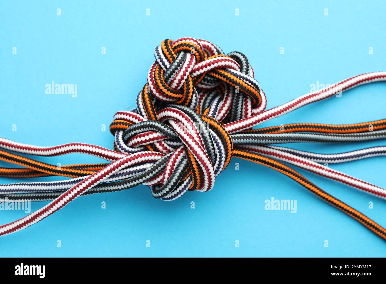 Colorful ropes tied in knot on light blue background. Unity concept ...