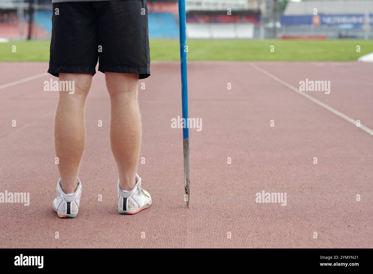 Athlete standing on track field wearing sports attire holding javelin ...