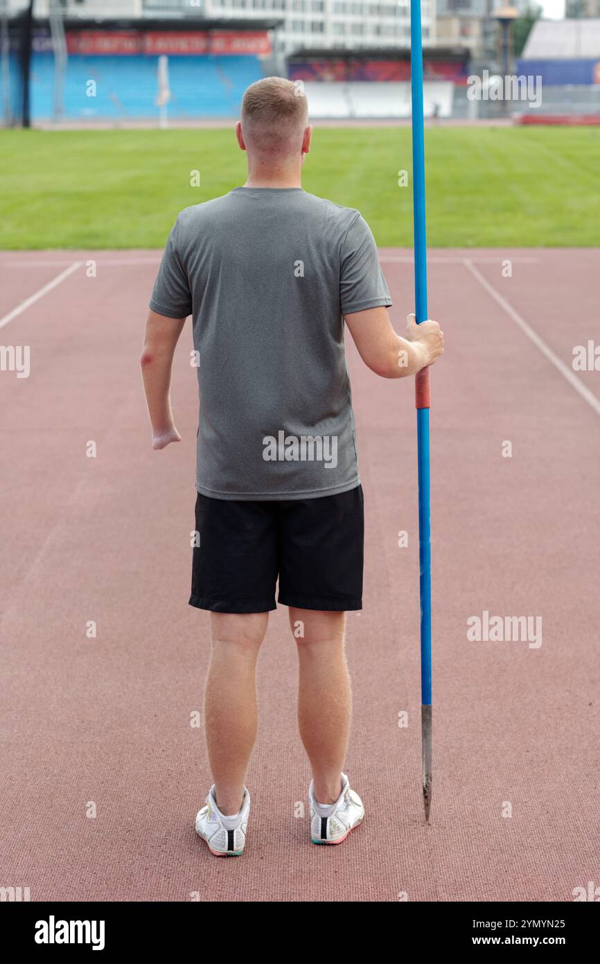 Athlets stands on athletic track holding a javelin in preparation for ...