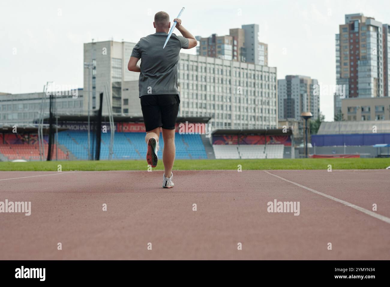 Athlete running at track while practicing javelin throw technique in ...