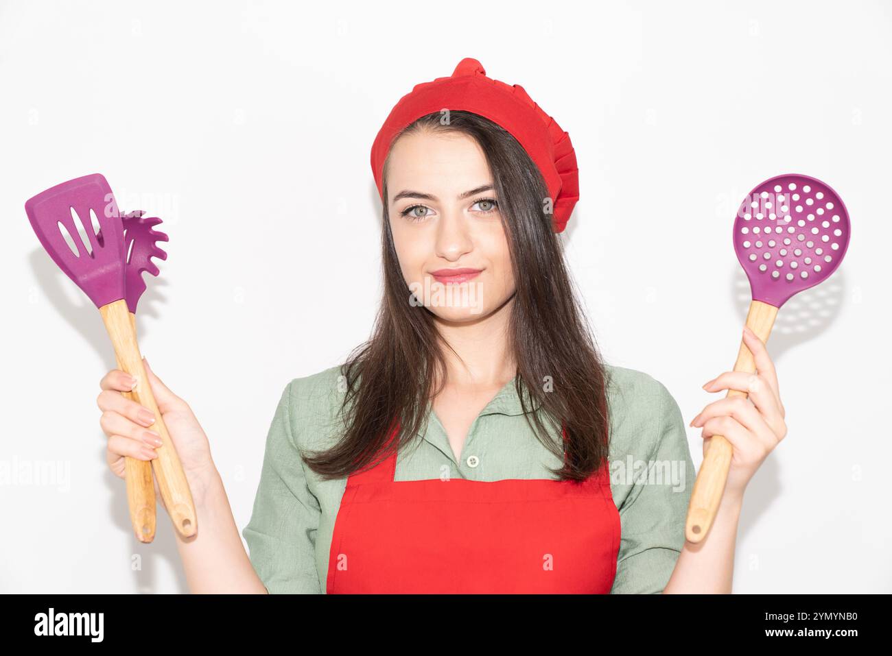 Portrait of young woman chef wearing red apron isolated white color ...