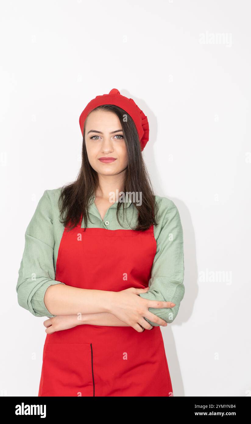 Portrait of young woman chef wearing red apron isolated white color ...