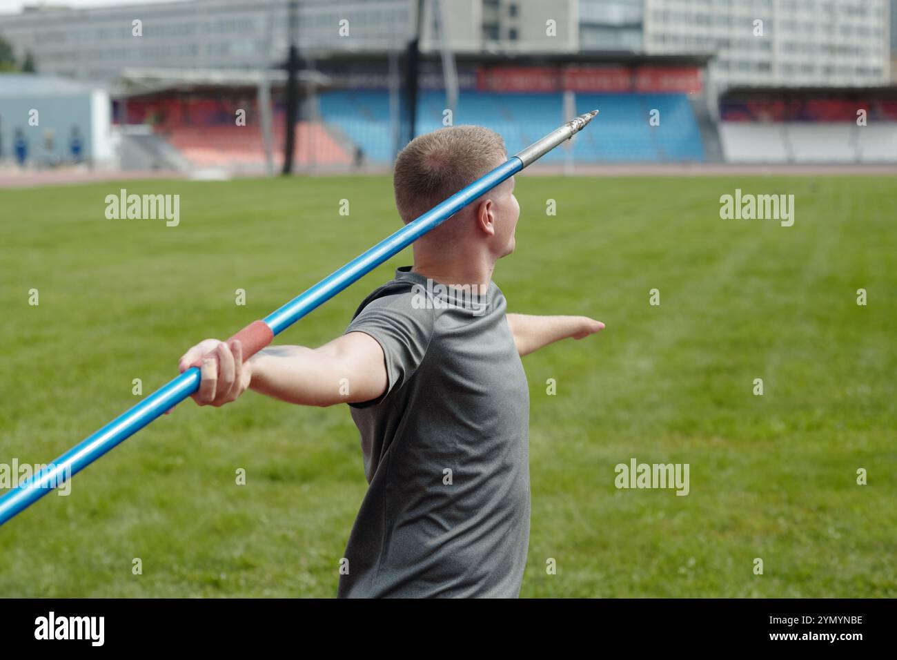 Young athlete practicing javelin-throwing technique on sports field ...