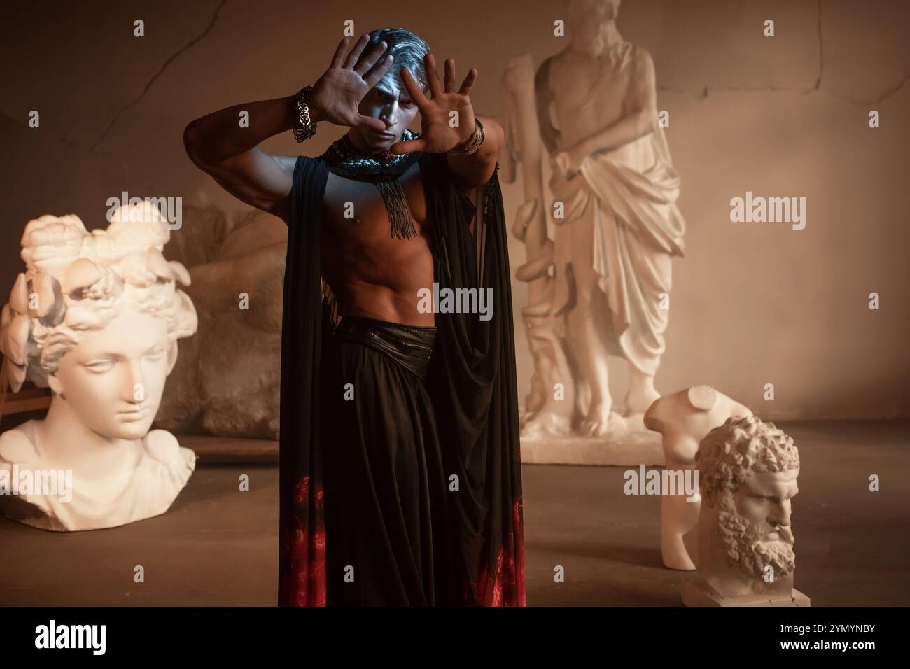 Muscular charismatic bodybuilder model in a silk cape makes an ...