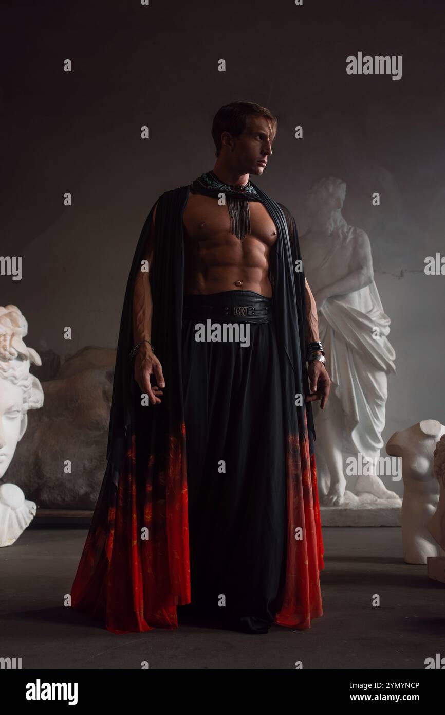 Muscular charismatic bodybuilder model in a silk cape makes an ...