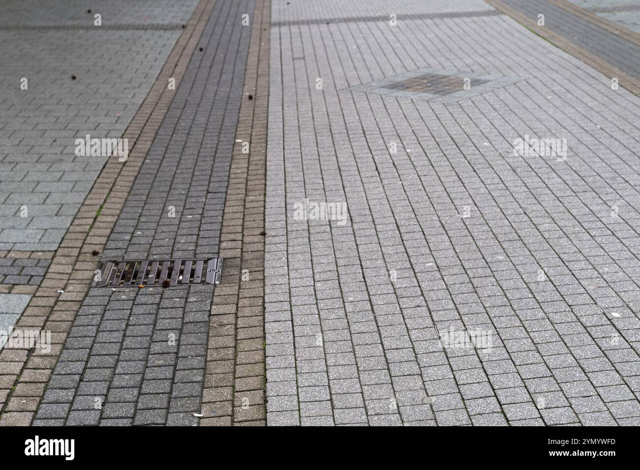 Deserted paved pedestrian zone with gully cover Stock Photo - Alamy