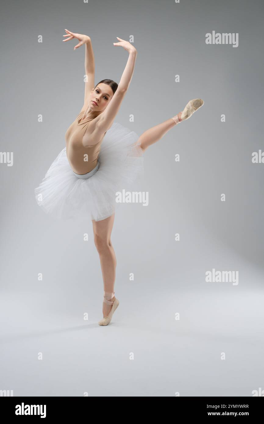 Dancer performs an elegant ballet pose against a neutral background ...