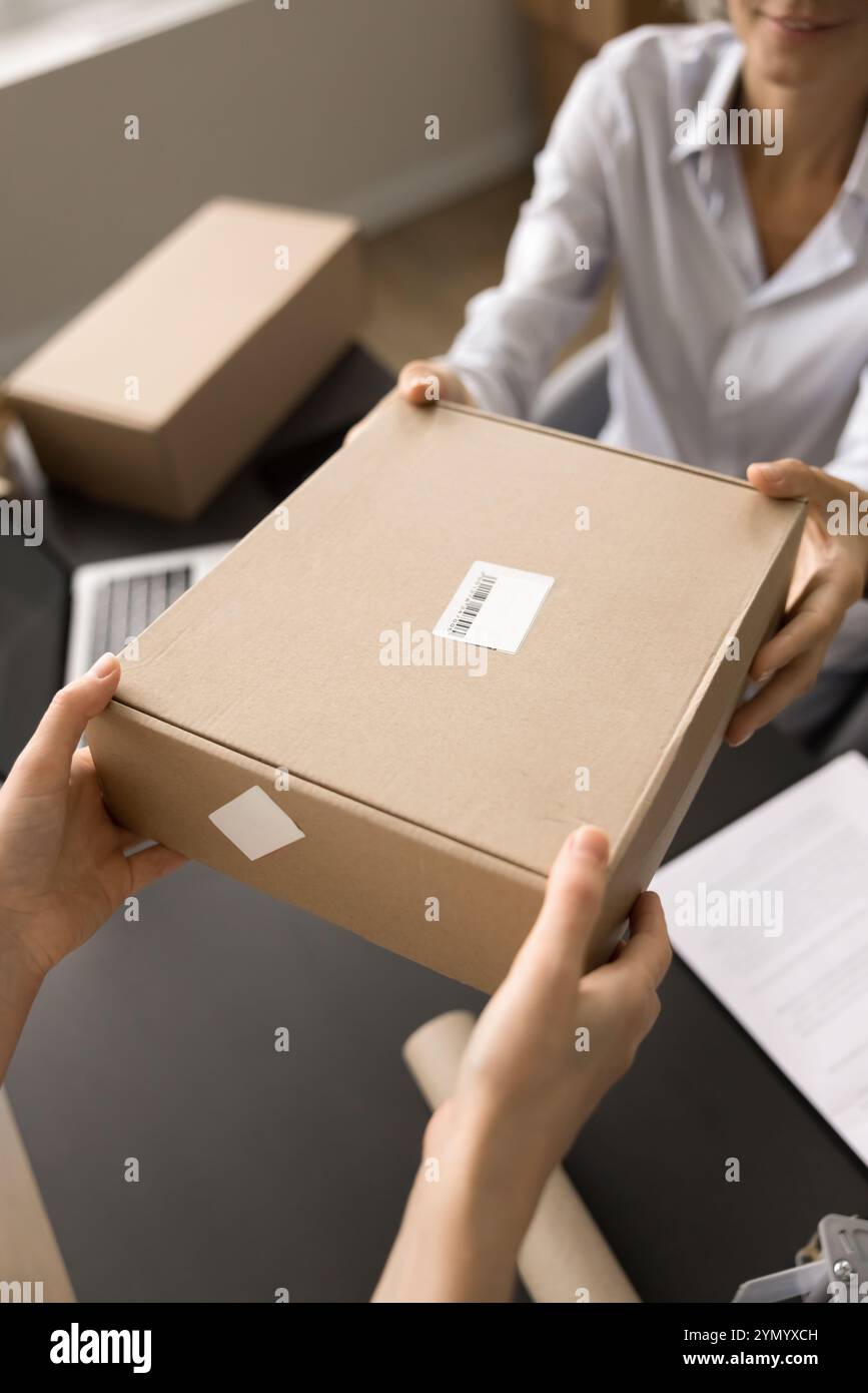 Internet shop storage worker giving cardboard box to female customer ...