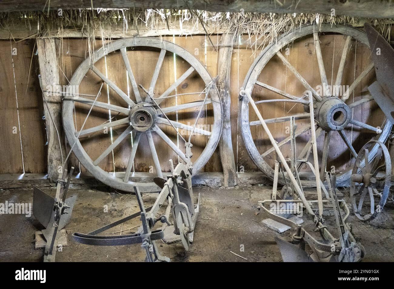 Wooden spoked wheels and plows in barn Stock Photo - Alamy