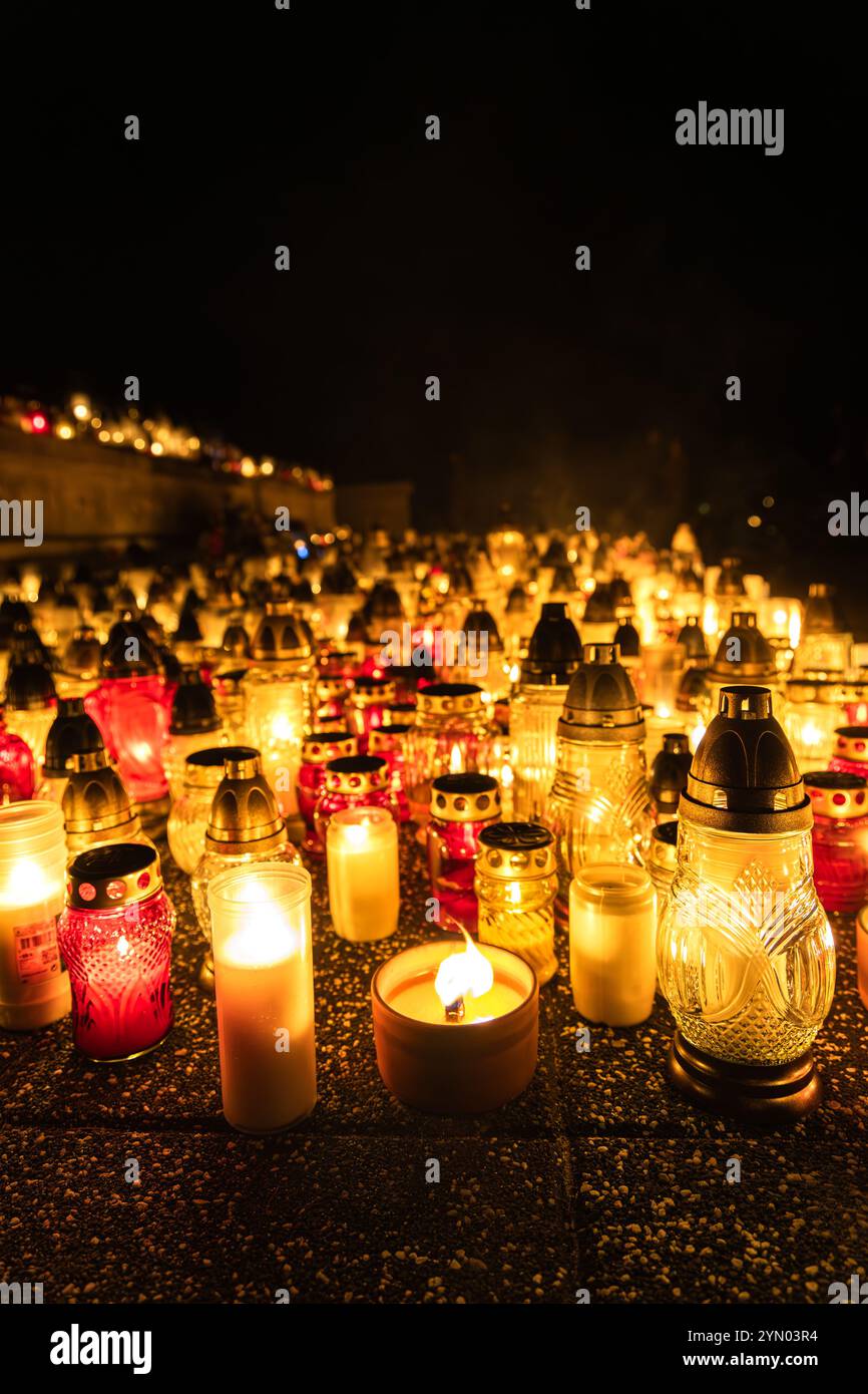 Rows of glowing cemetery candles at night during All Saints’ Day. A ...