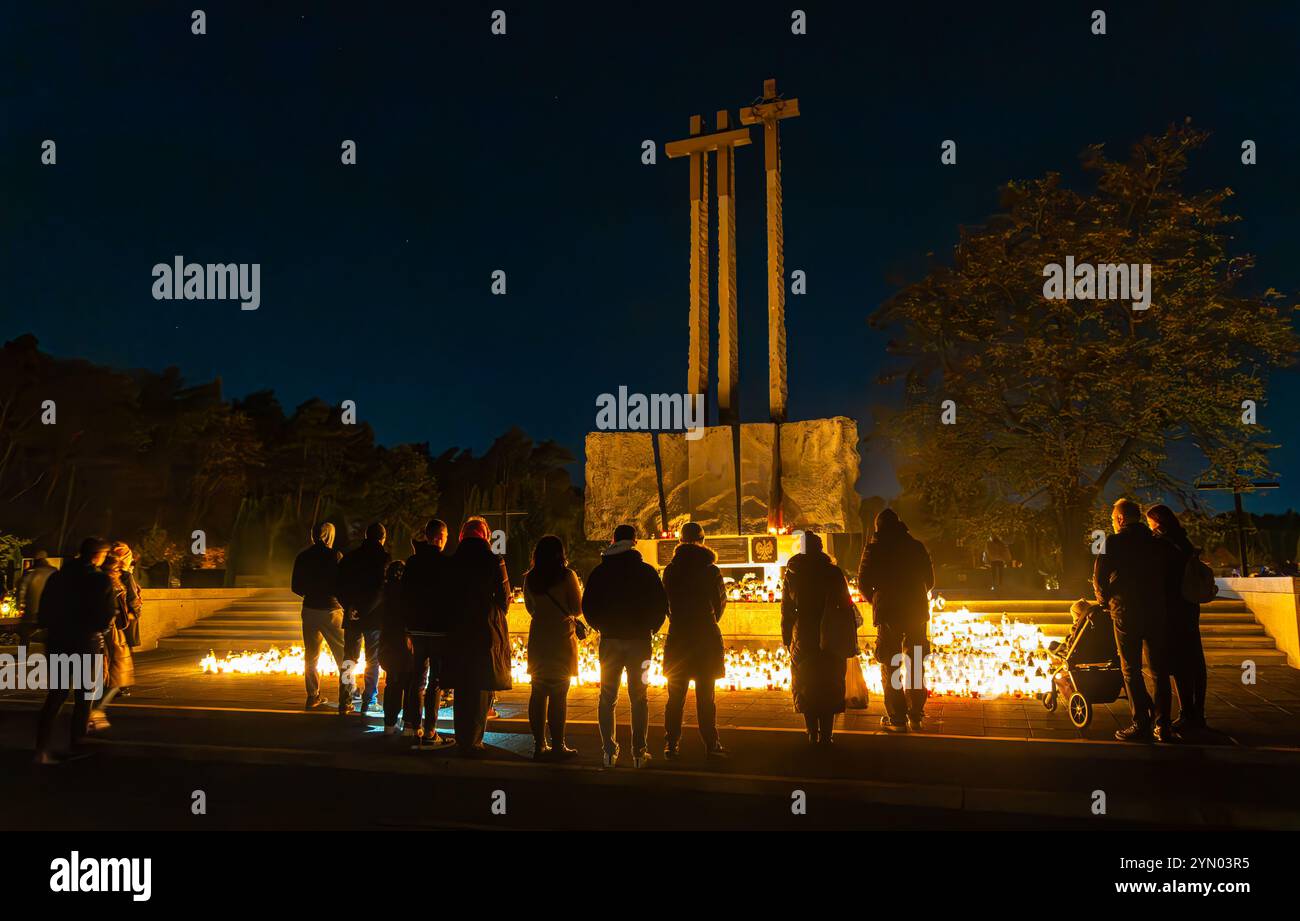 A solemn night scene of people gathered around a monument, lighting ...