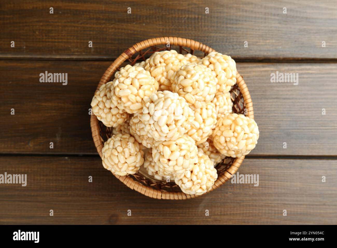Tasty puffed rice balls in wicker basket on wooden table, top view ...