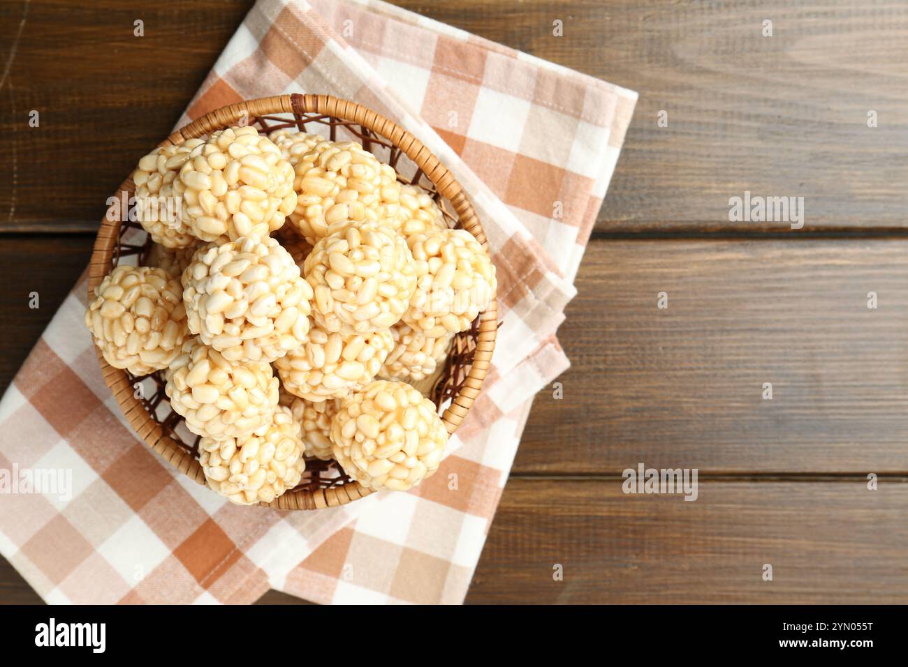 Tasty puffed rice balls in wicker basket on wooden table, top view ...