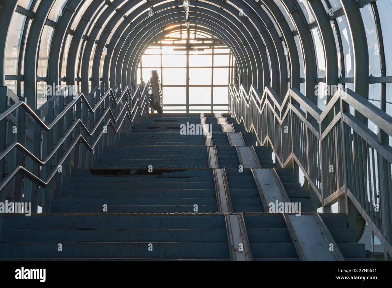 A covered pedestrian bridge featuring metal stairs and glass panels ...
