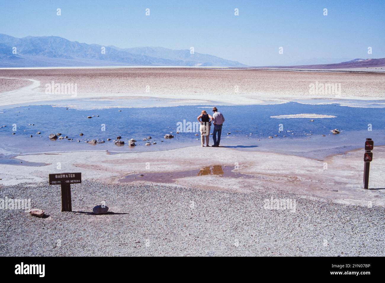 Two people stand by a small lake at Badwater Basin in Death Valley ...