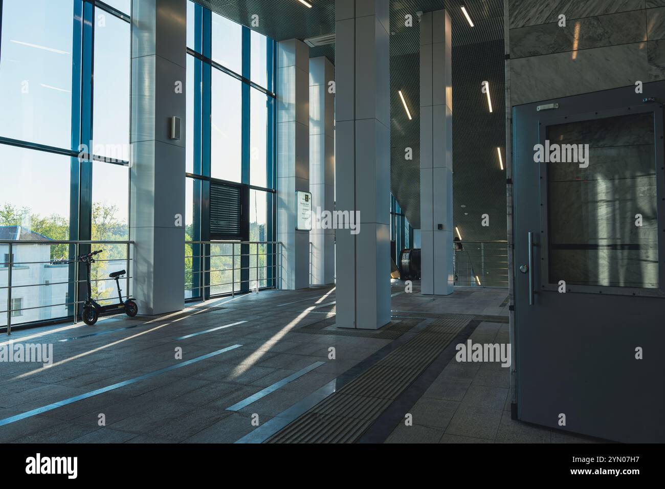 A spacious modern train station interior with glass walls and sunlight ...