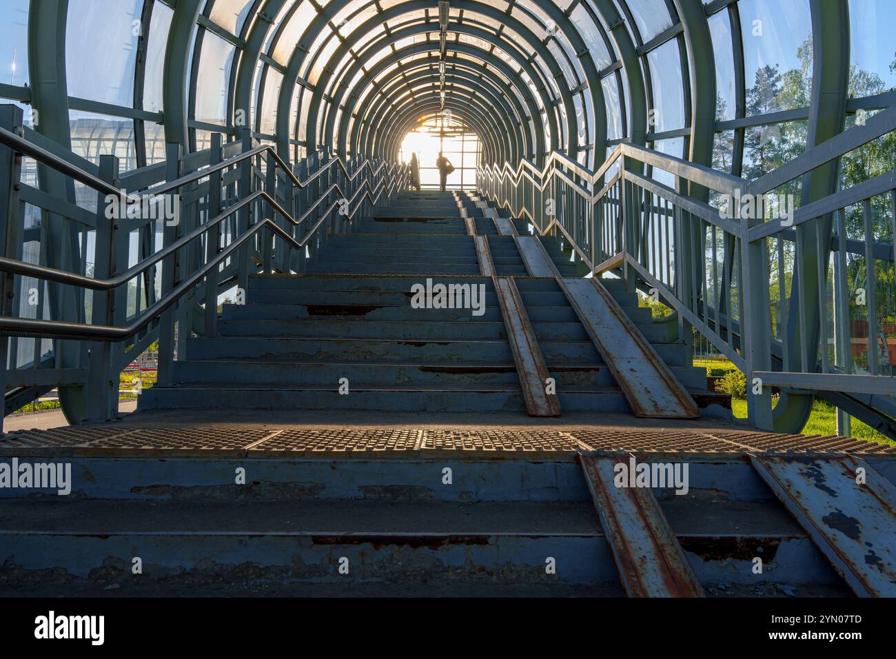 A covered pedestrian bridge featuring metal stairs and glass panels ...