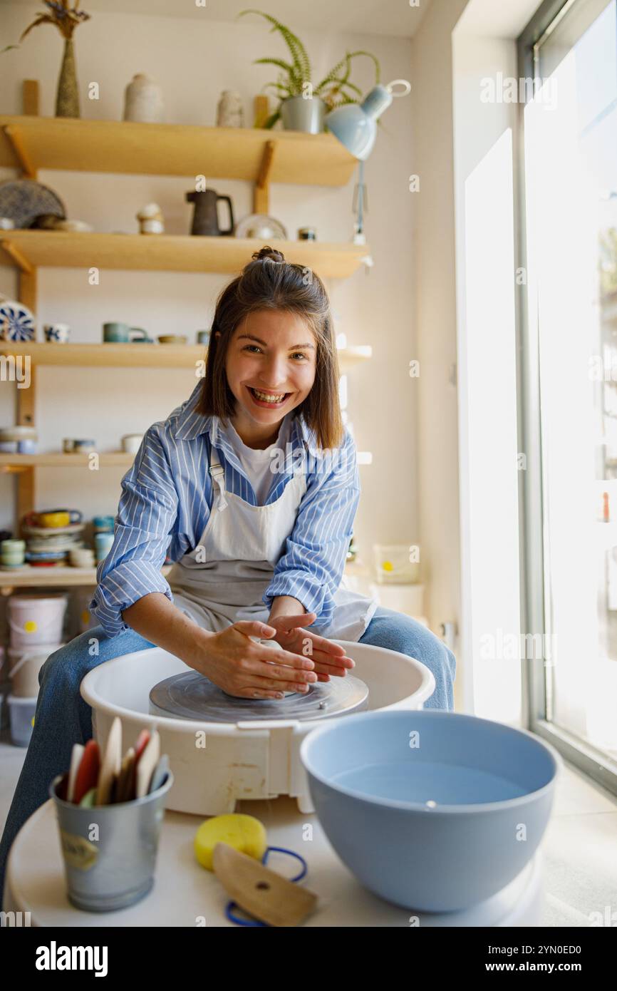 A joyful and smiling artist passionately creates beautiful pottery in a ...