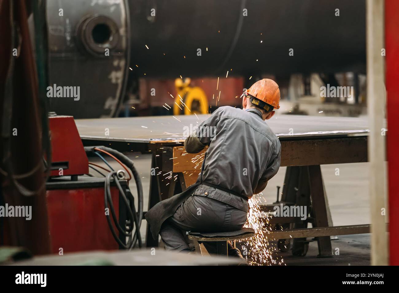 Worker cleans metal part using grinding machine in metalworking ...