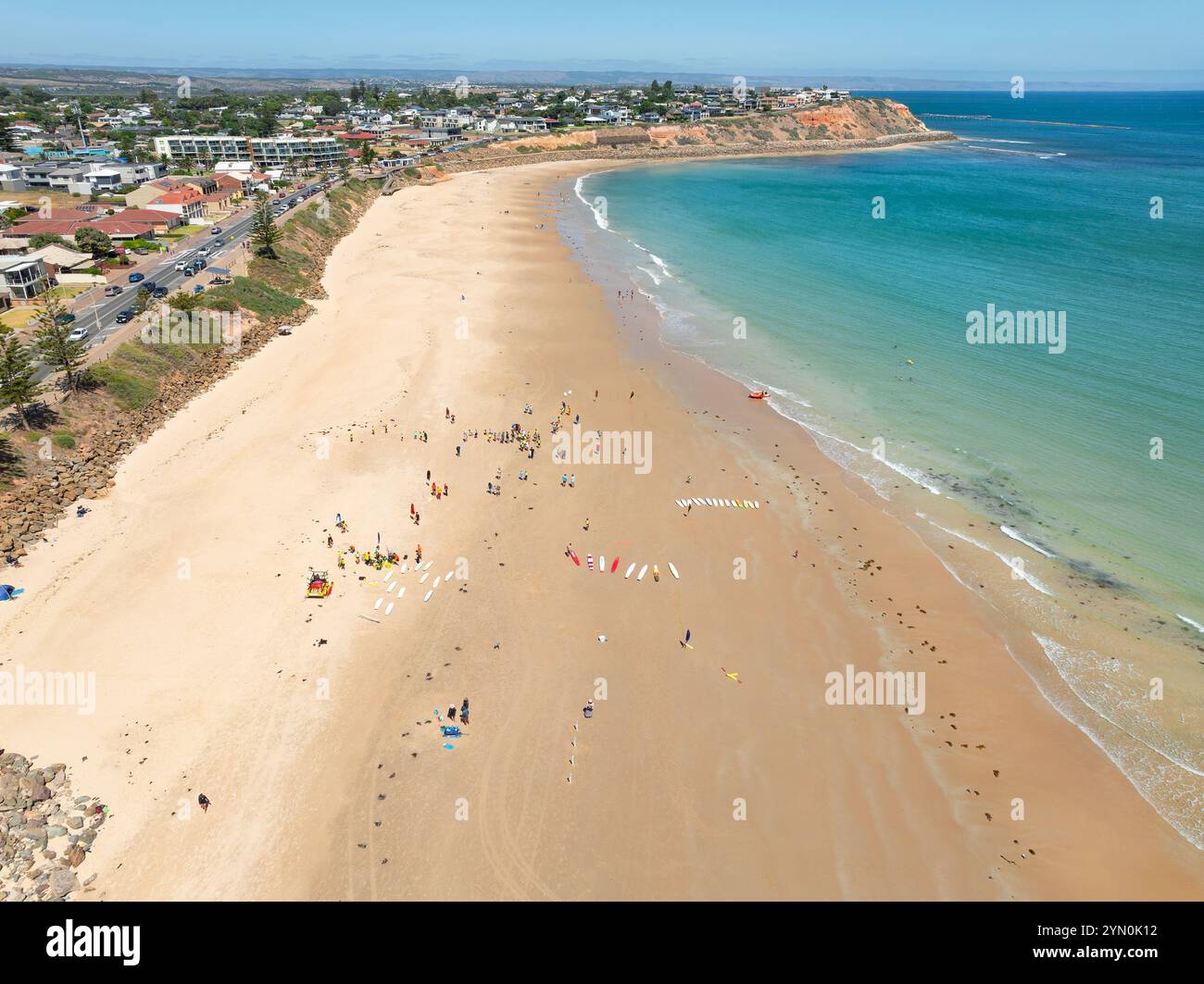 Aerial view of beachgoers on a wide sandy beach below a coastal town at ...