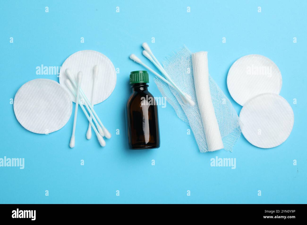 Topical iodine, bandage, cotton pads and swabs on light blue background ...