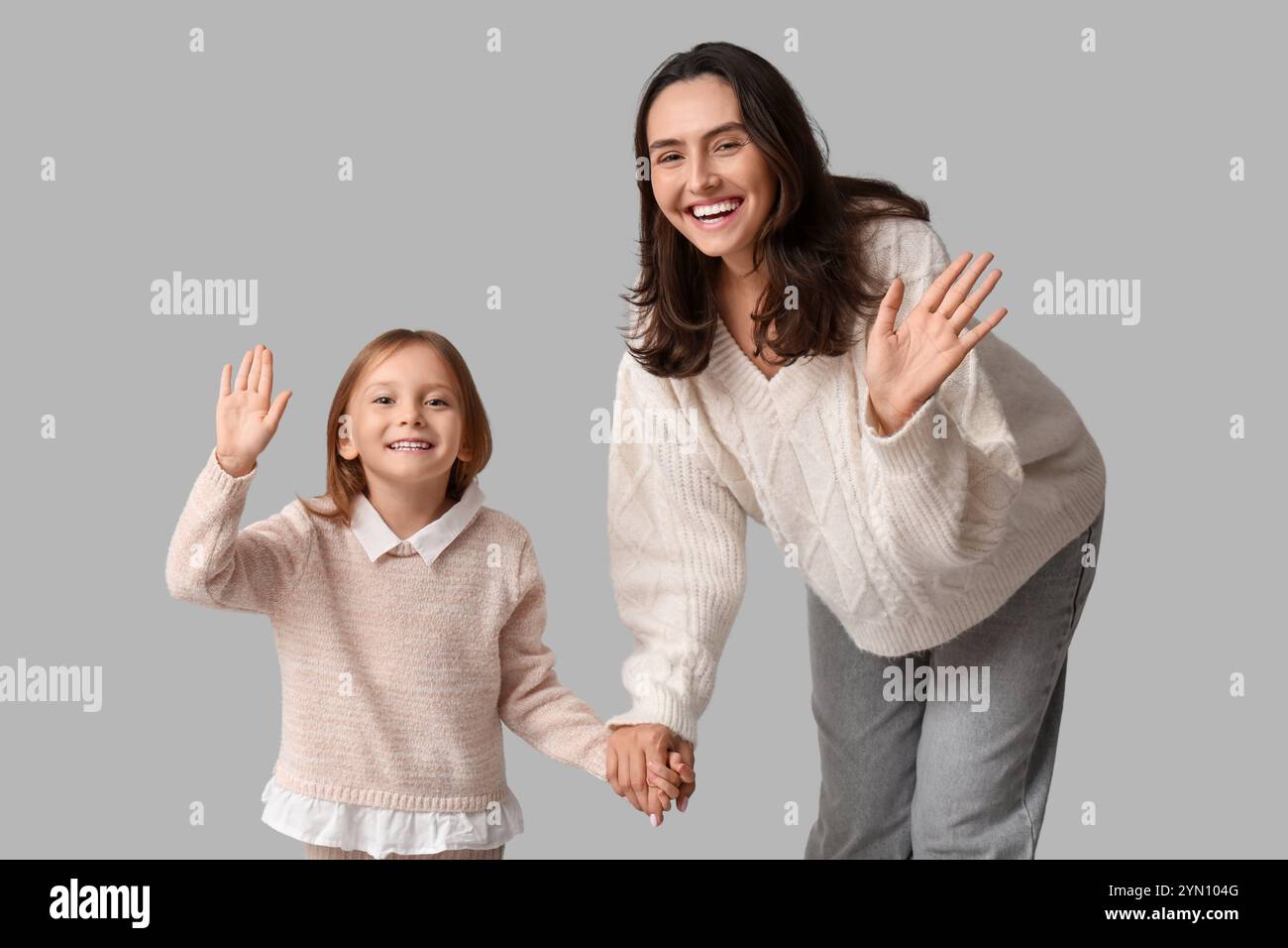 Mother and her little daughter waving hello on grey background Stock ...