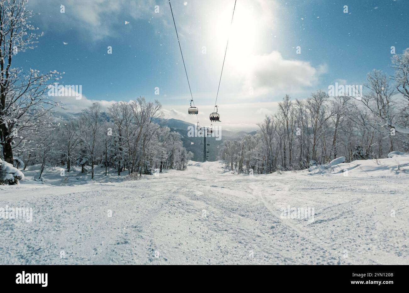 A ski lift moves upward through a winter landscape, surrounded by snow ...