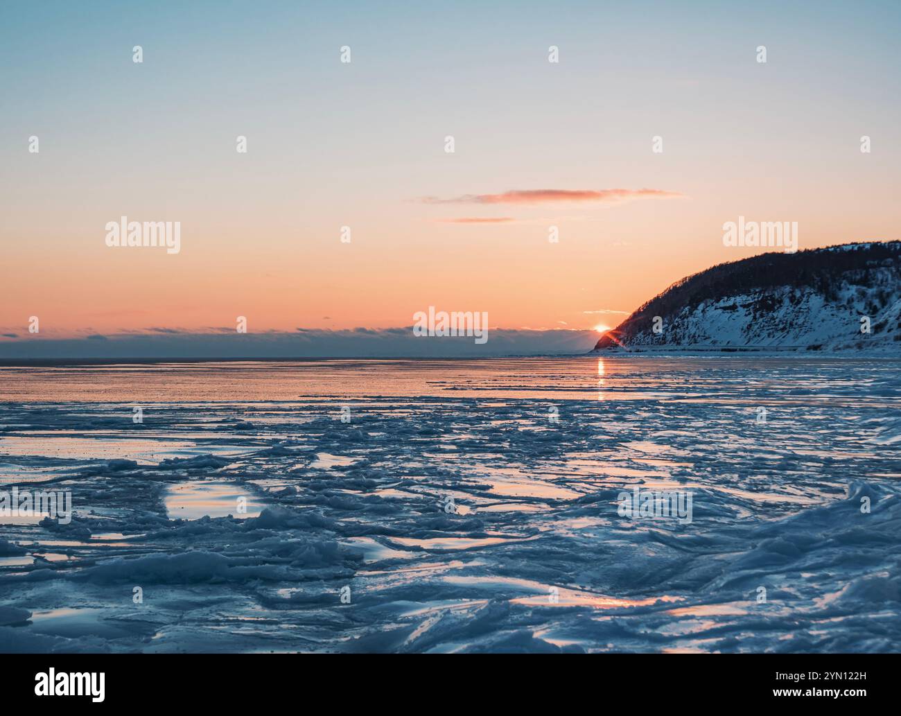 The sun sets over a frozen sea, casting a golden glow across the ice ...