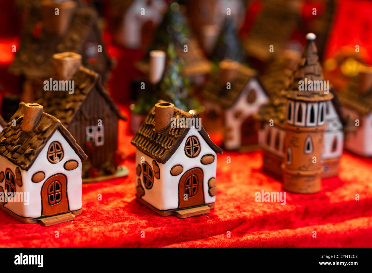 Detailed ceramic miniature houses and tower, arranged on red cloth ...