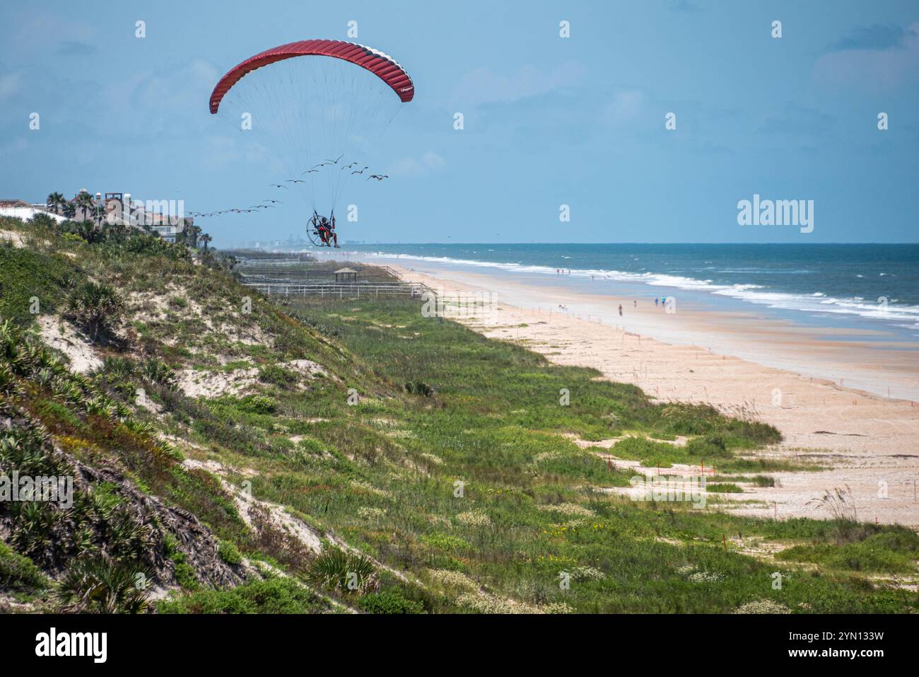 Paraglider flying a paramotoring wing and joined by a long line of ...
