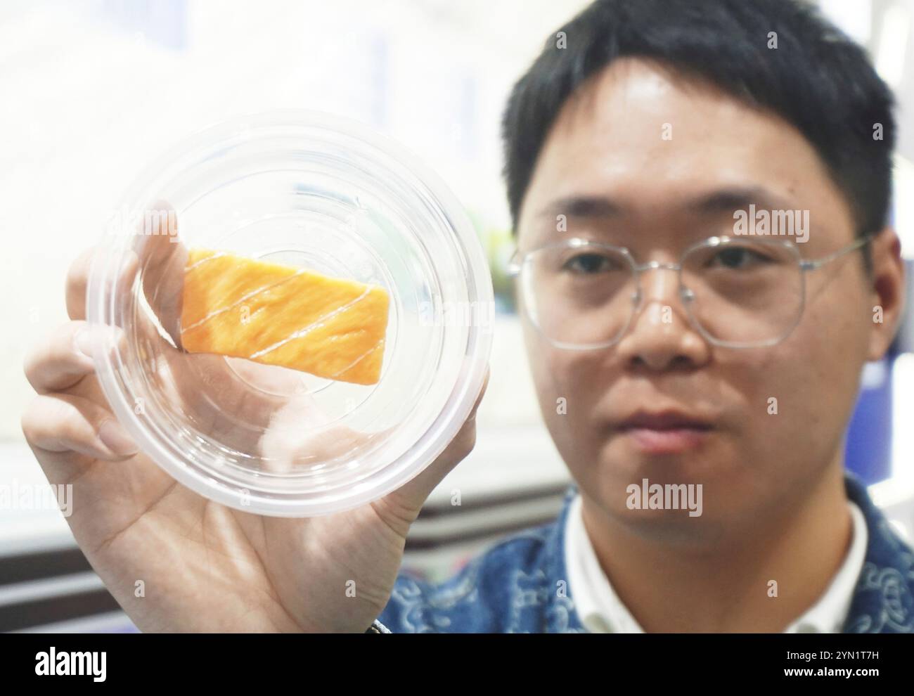 A researcher shows a piece of lab-grown rainbow trout meat during an ...