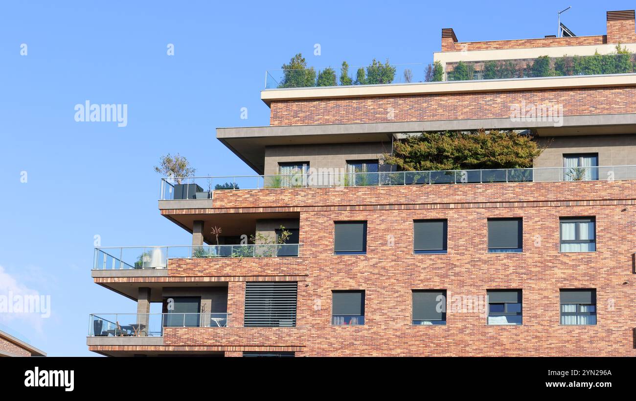 Modern brick residential building with balconies and roof garden under ...