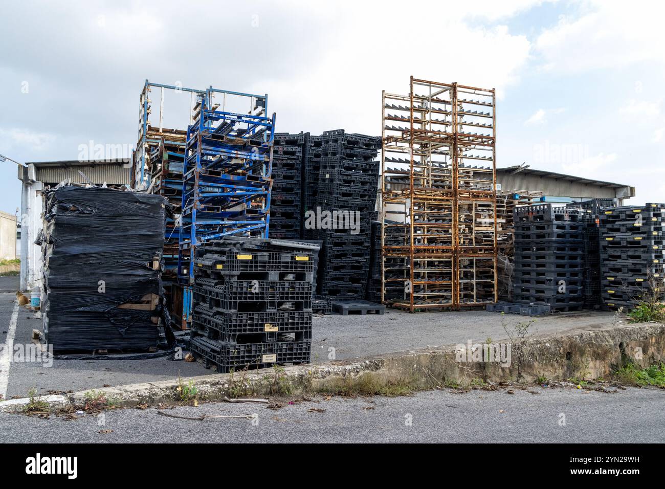 Industrial scene showing stacked plastic pallets, rusty metal ...