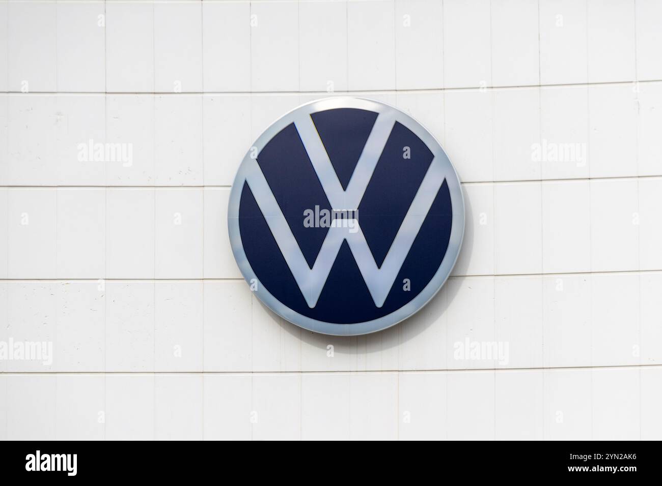 Close up of volkswagen logo mounted on white tiled wall, representing ...