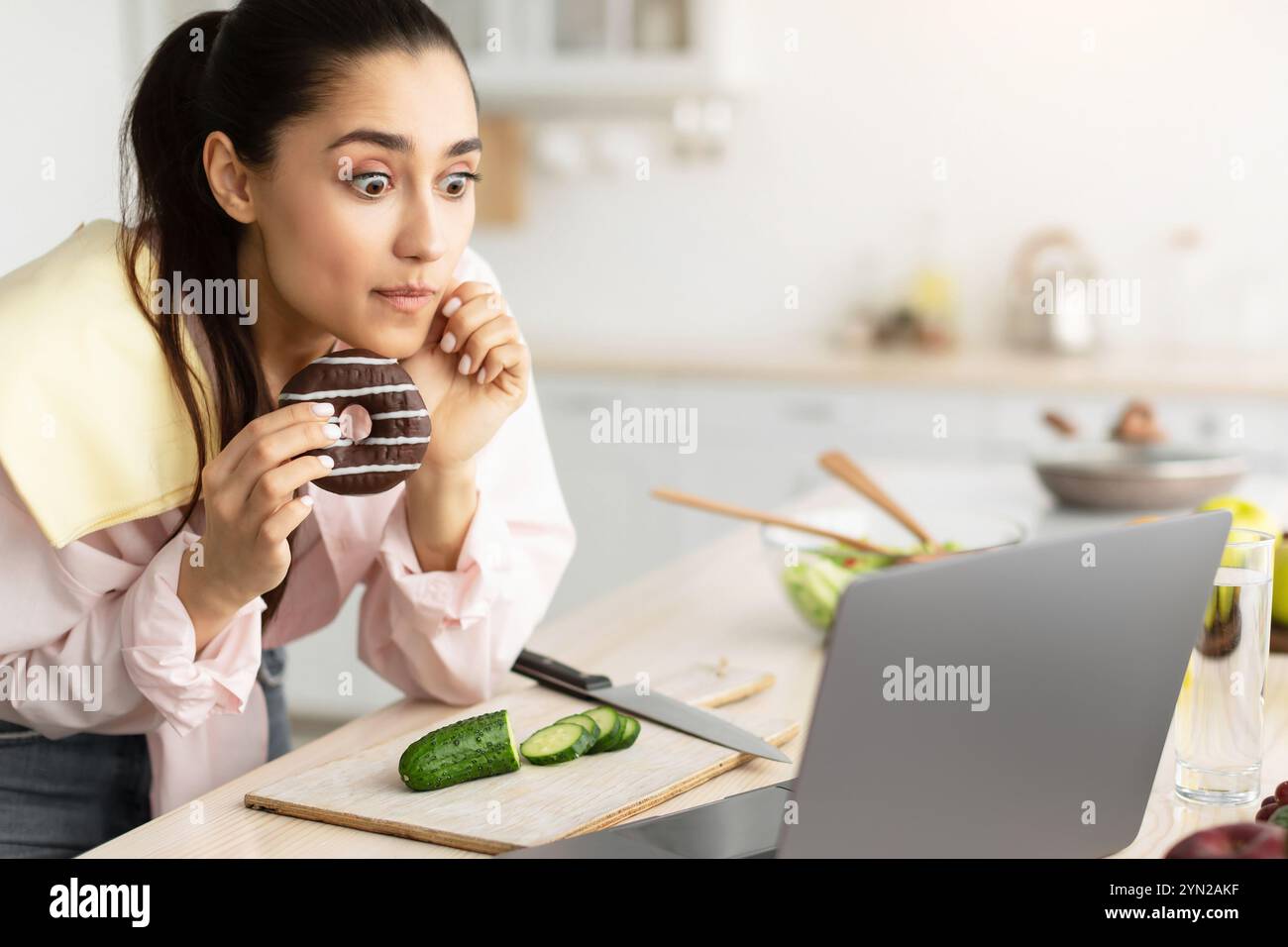 Surprised shocked woman watching movie using laptop eating sweet snack ...