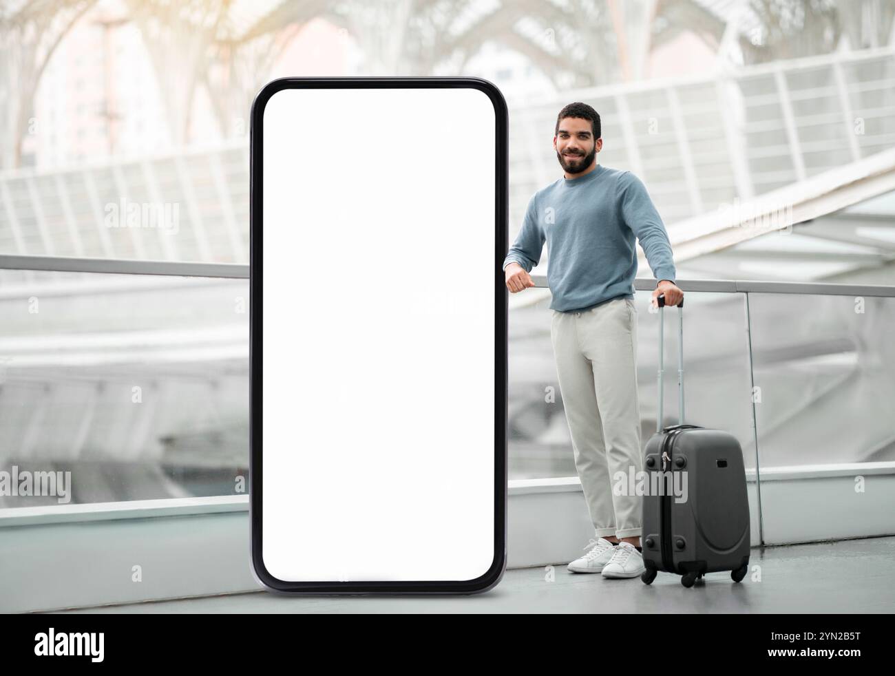 A traveler stands beside a blank advertising board in an airport ...